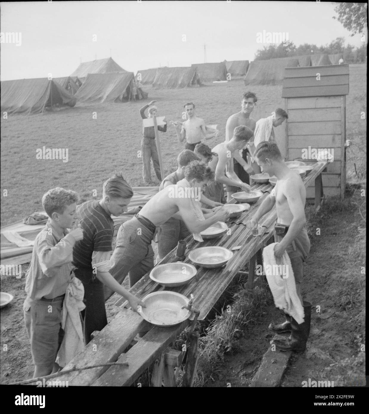 Youth Service Volunteers wash, shave, and brush teeth at basins on a ...
