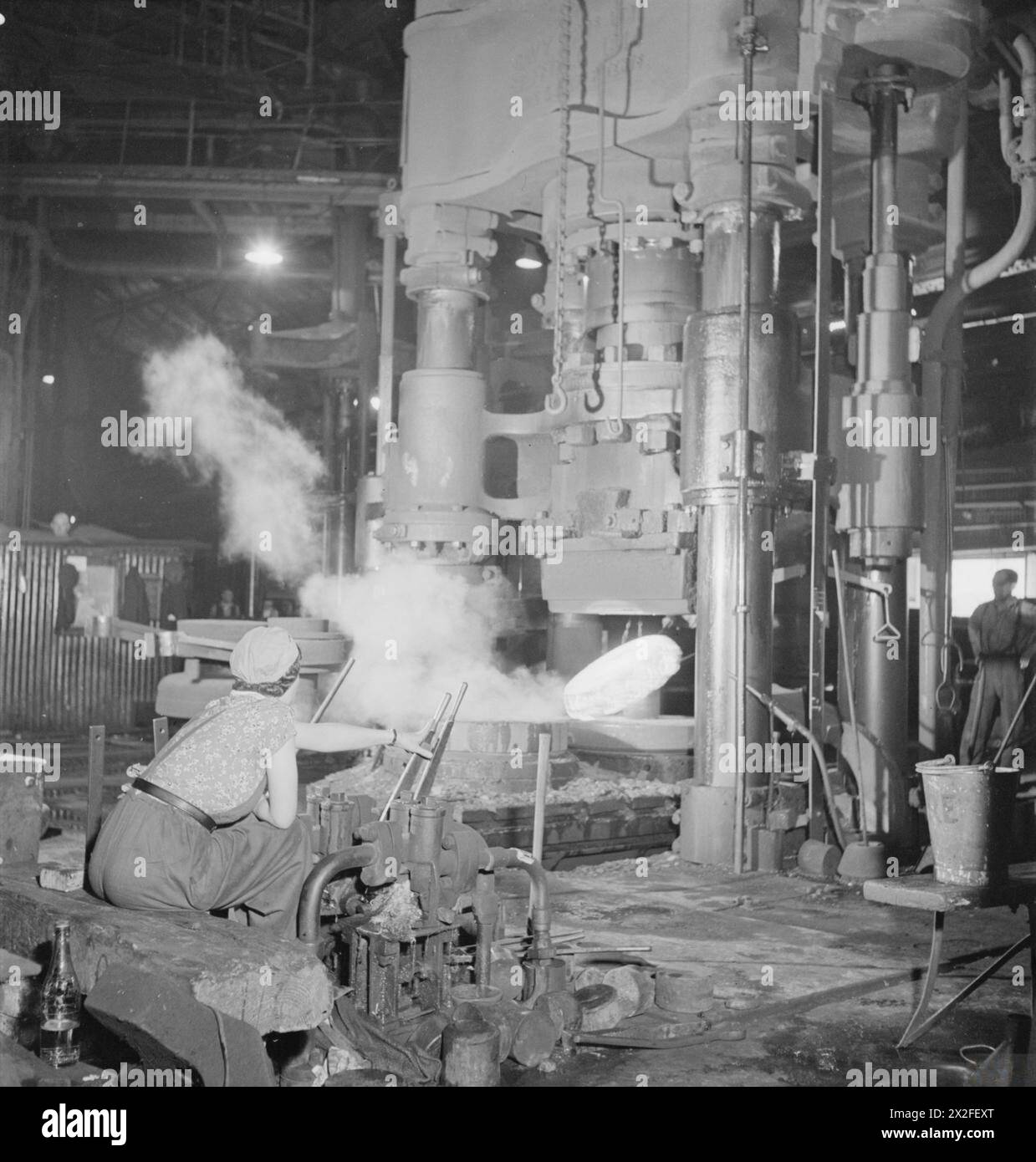 A woman metal worker operates a 2,000 lb metal pressing machine ...