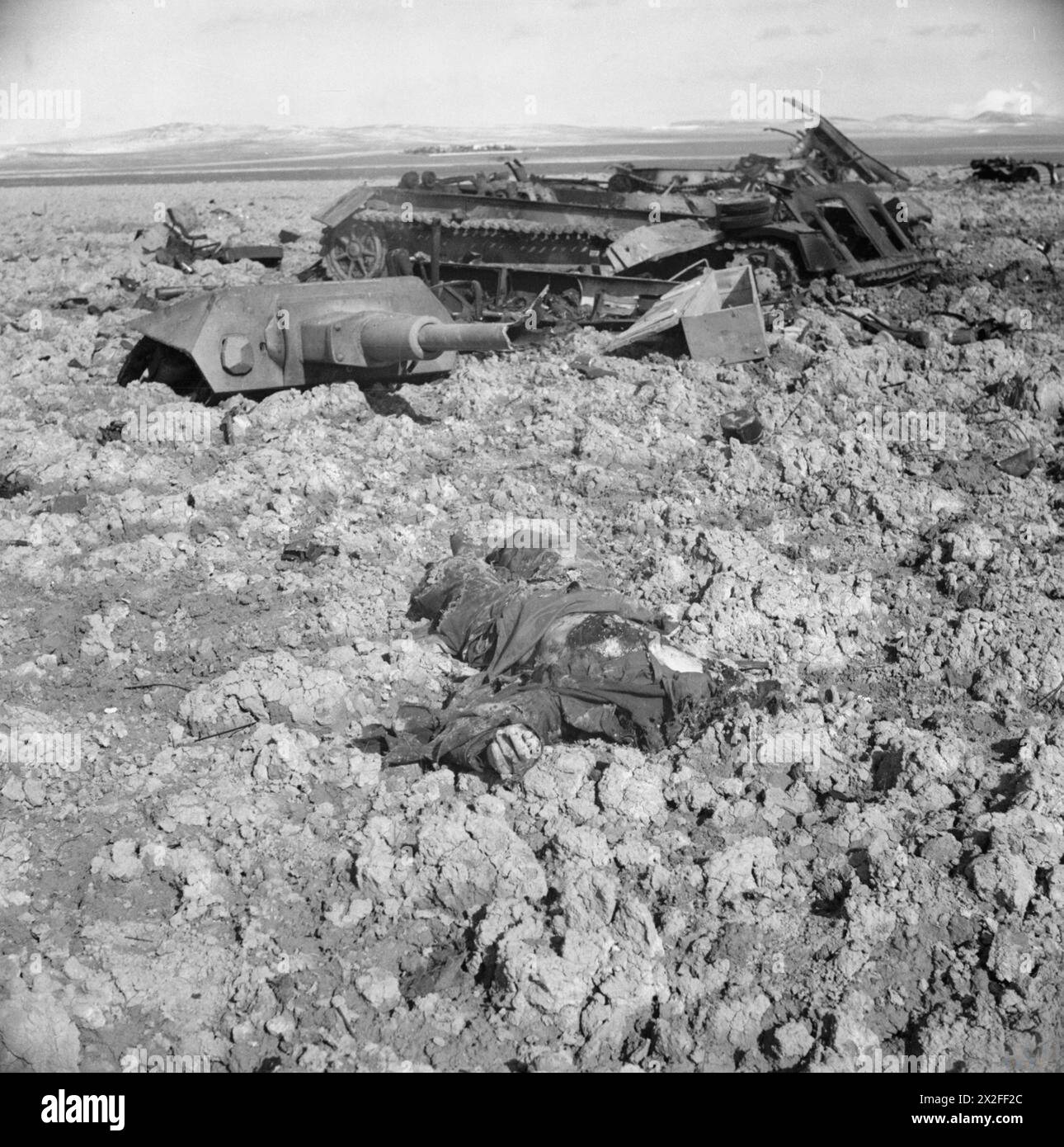 A German Panzer IV tank with its gun turret destroyed lies in a field ...