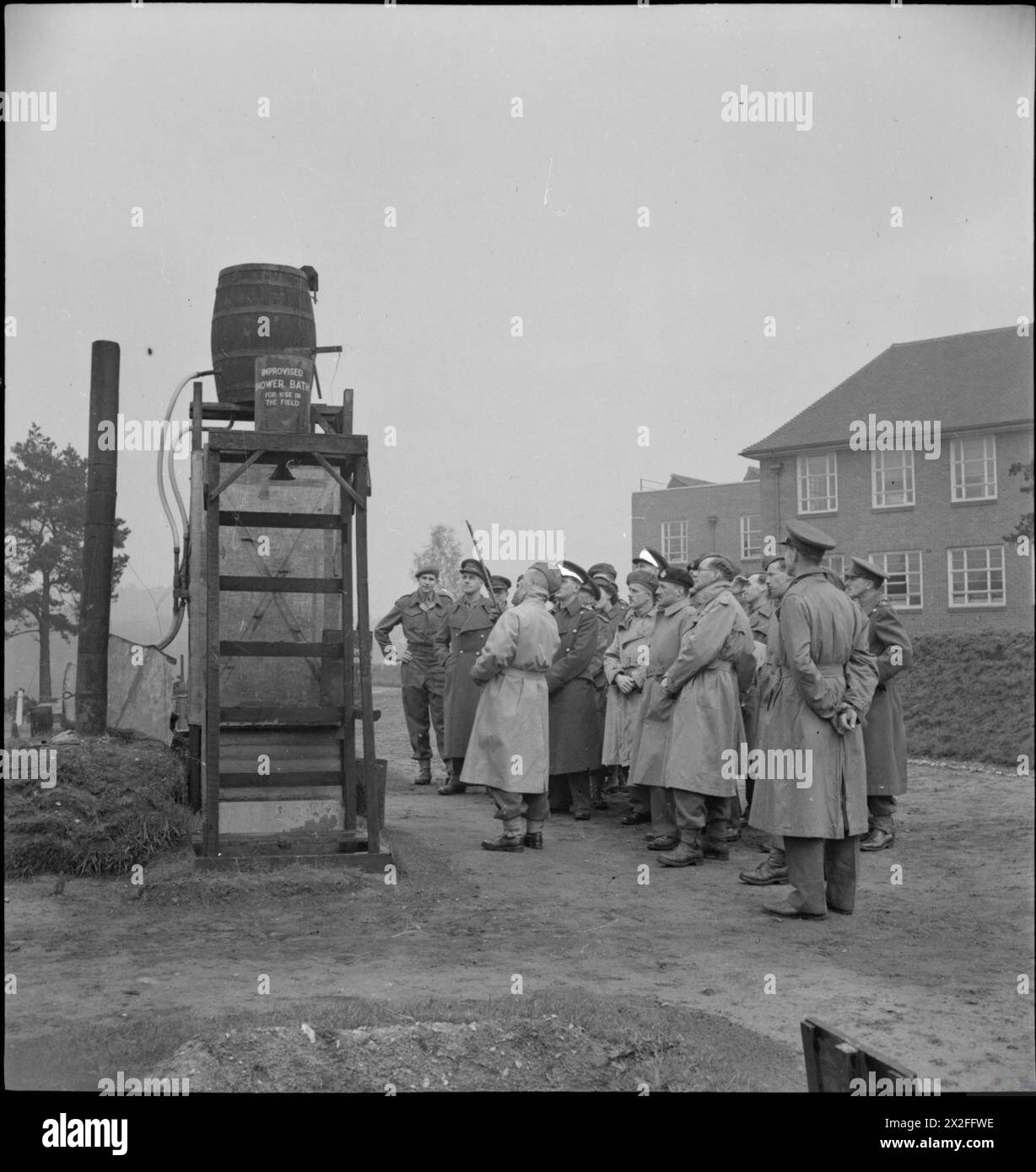 British officers observe a demonstration of an improvised field shower ...