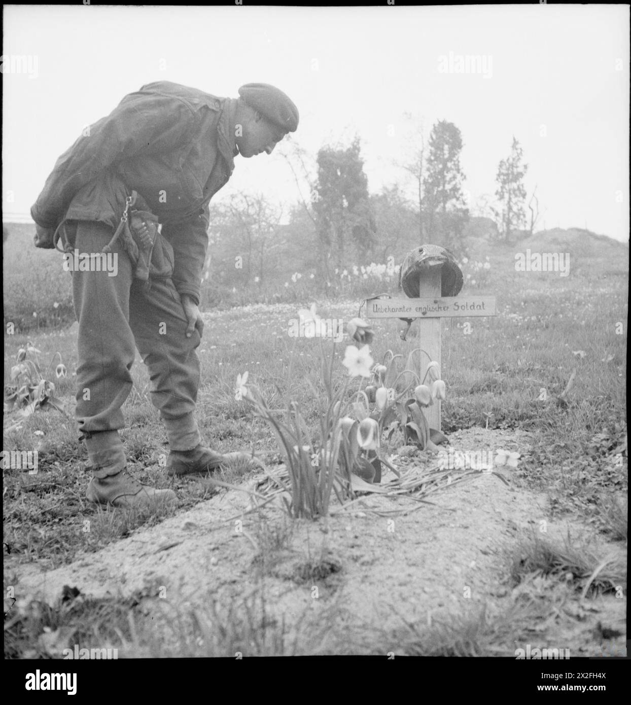 A British soldier inspects the grave of a 1st Airborne Division soldier ...