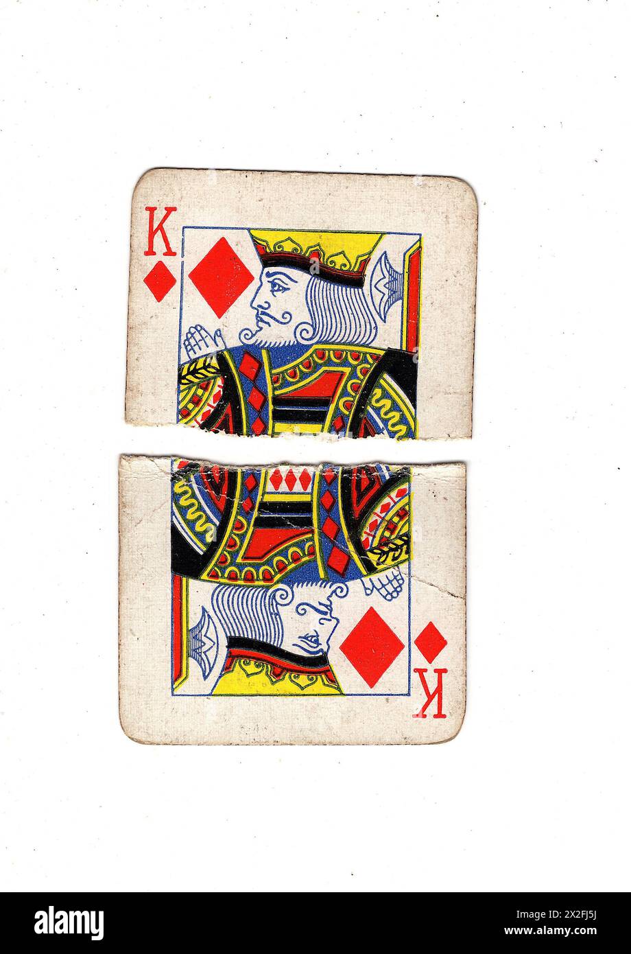 A vintage, well used king of diamonds playing card torn in half on a ...