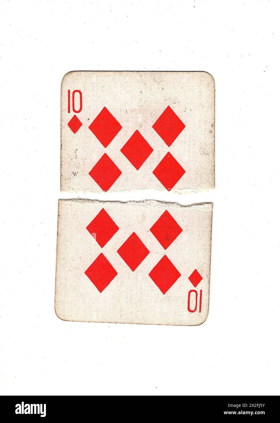A vintage, well used ten of diamonds playing card torn in half on a ...