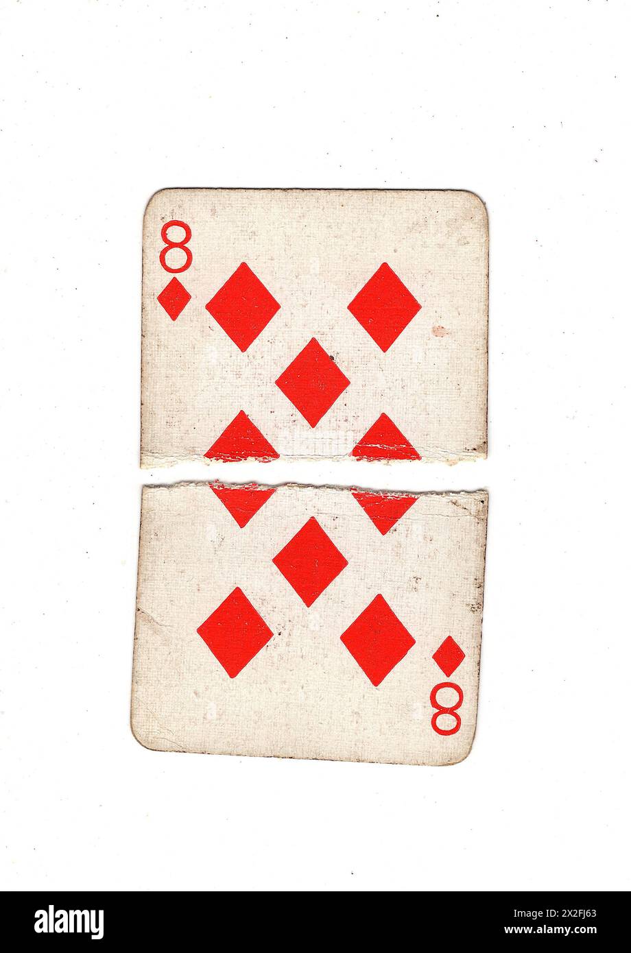 A vintage, well used eight of diamonds playing card torn in half on a ...