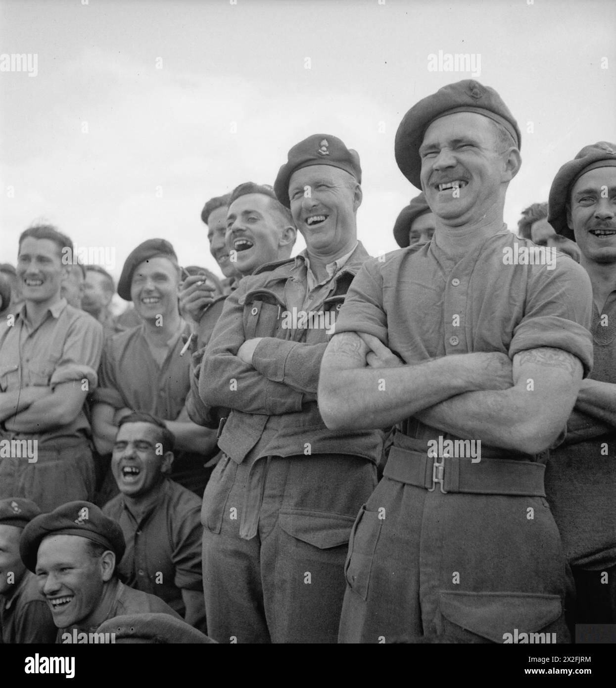 GEORGE FORMBY IN NORMANDY - A cheerful group of soldiers laughing at one of George Formby's ...