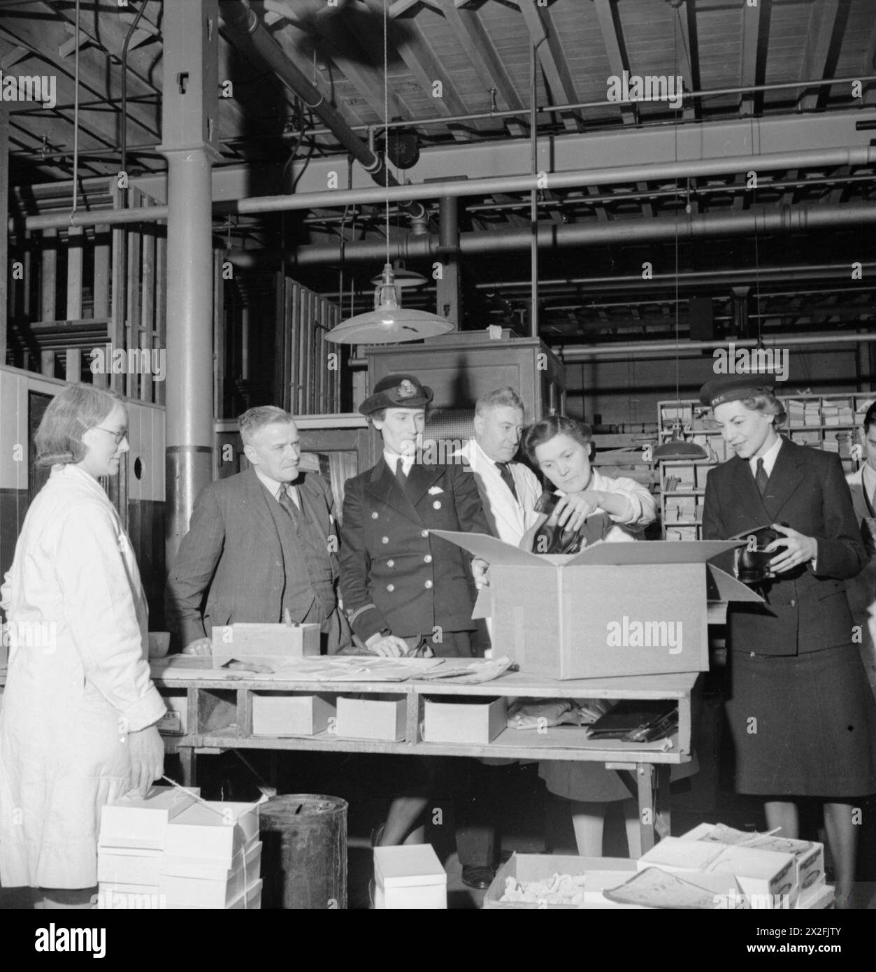 Wren officers and ratings observe the packing of shoes into 12-pair ...