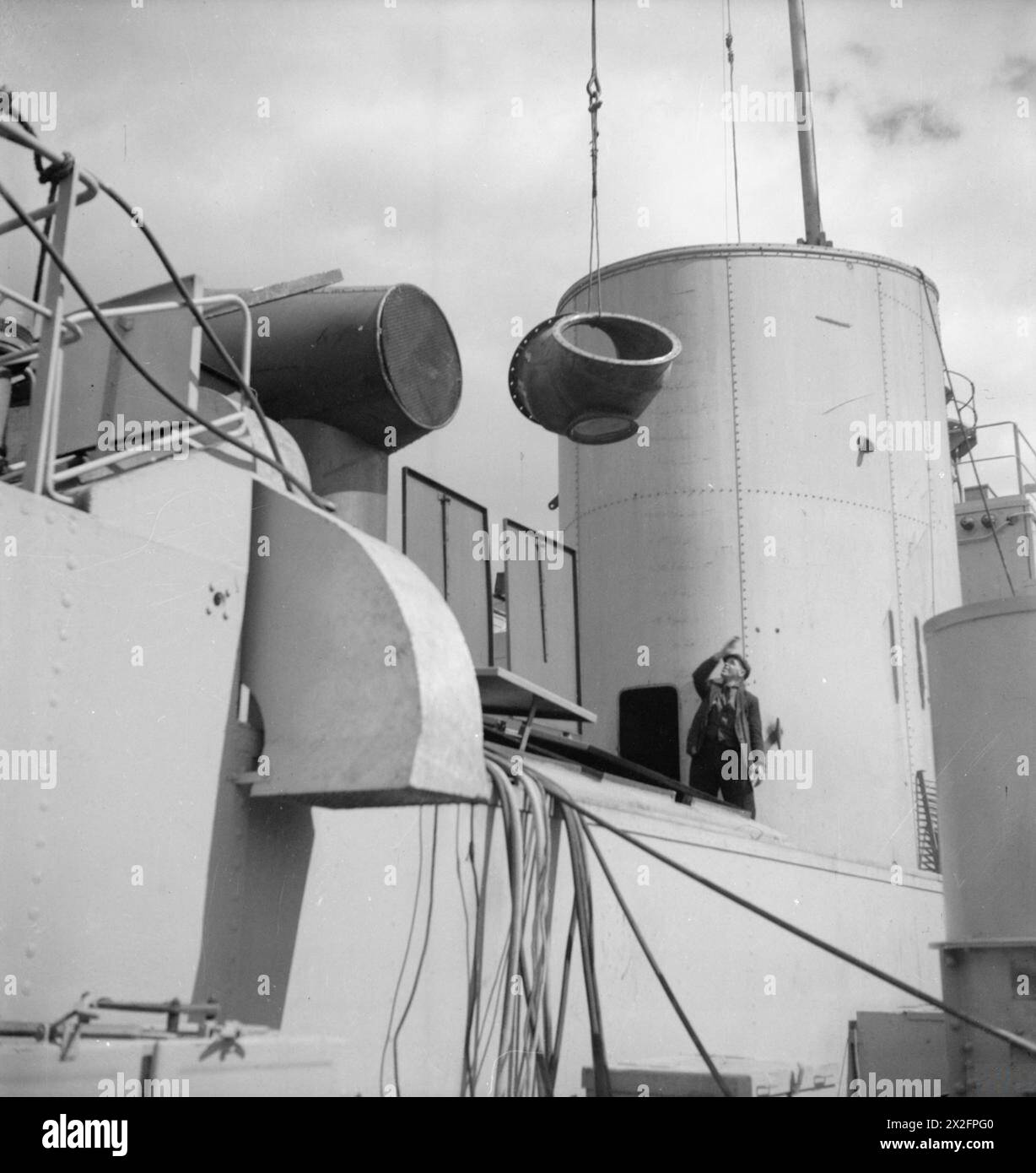 Parts of a boiler are hoisted onto a ship under construction at a ...