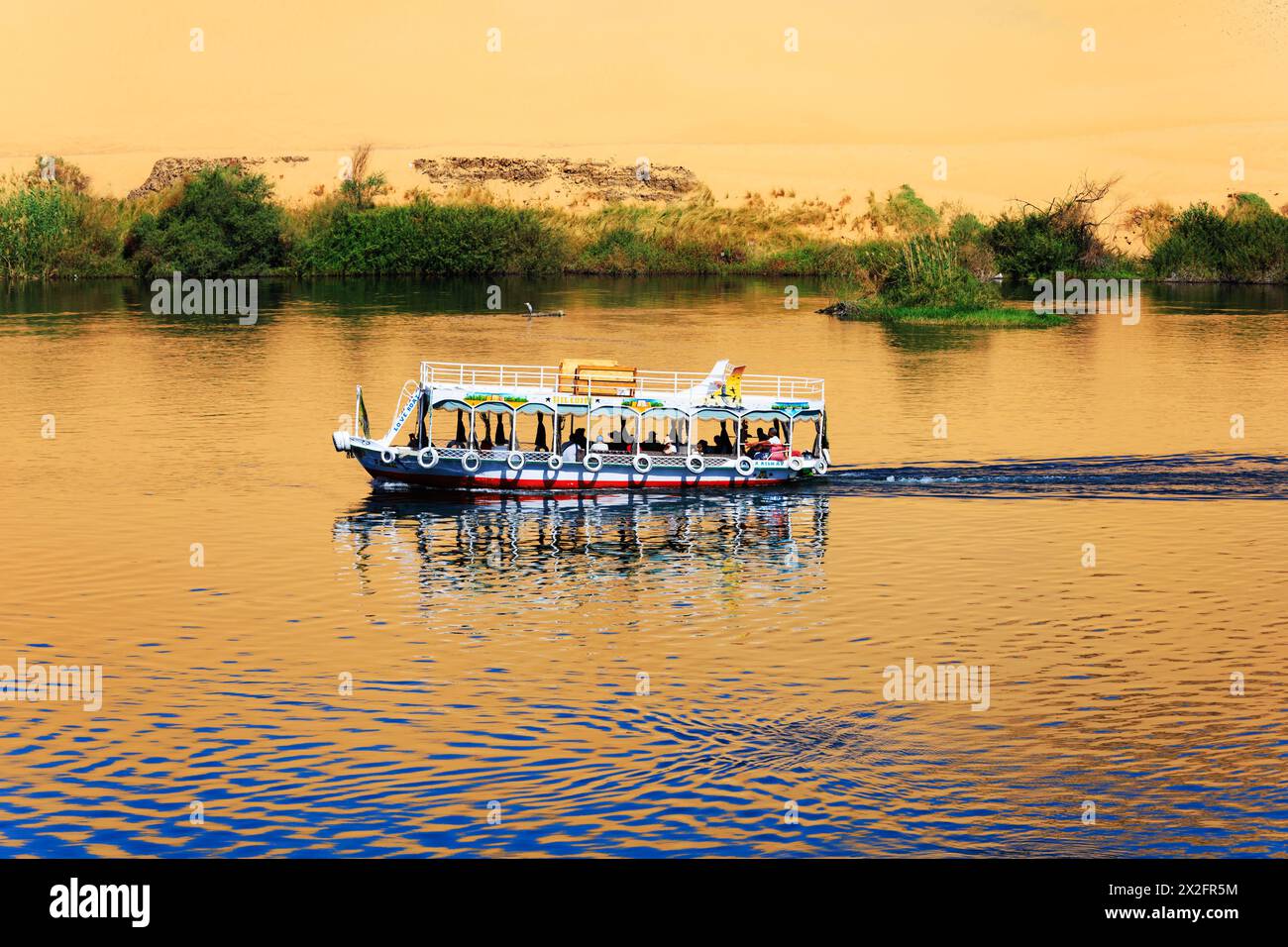 Tourist river boat on the River Nile, with golden reflections from the ...