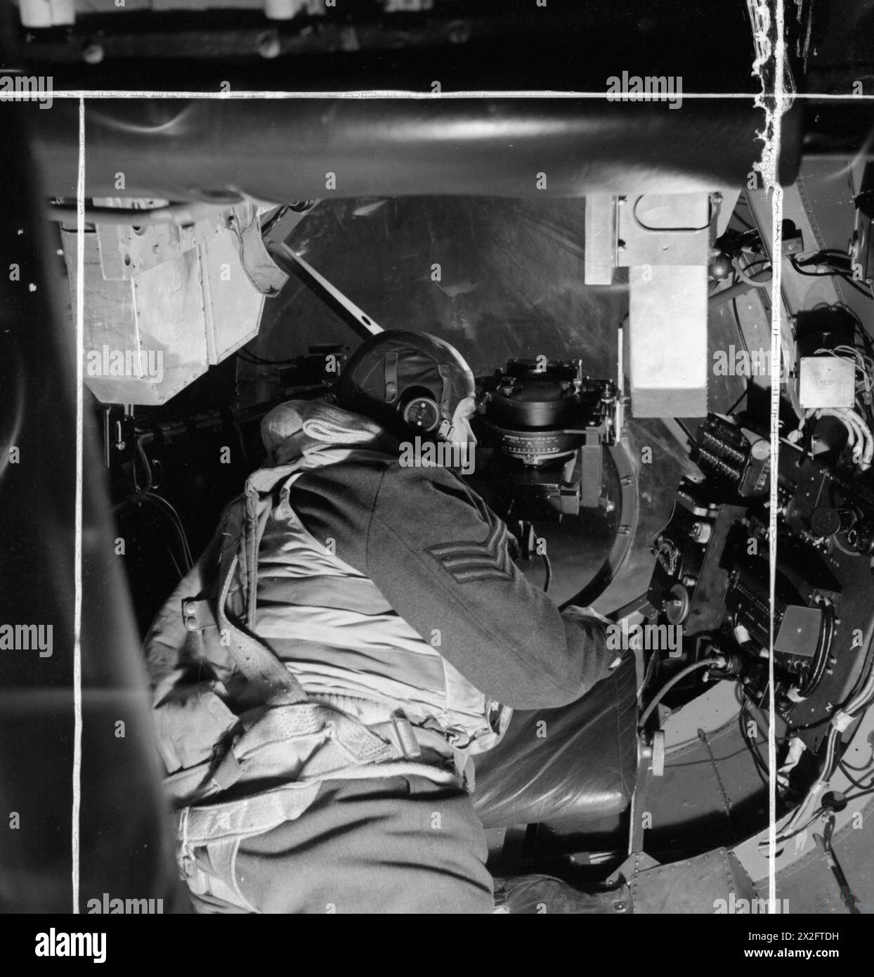 A bomb aimer in an Avro Lancaster checks instruments at his position ...
