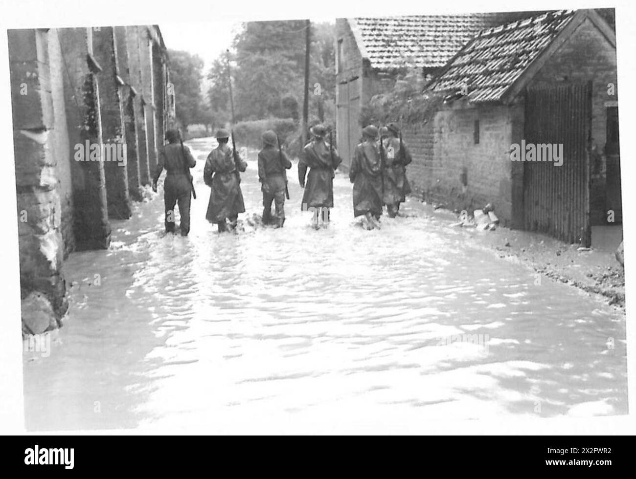FLOOD SCENES IN NORMANDY - Soldiers walking through a flooded street in ...
