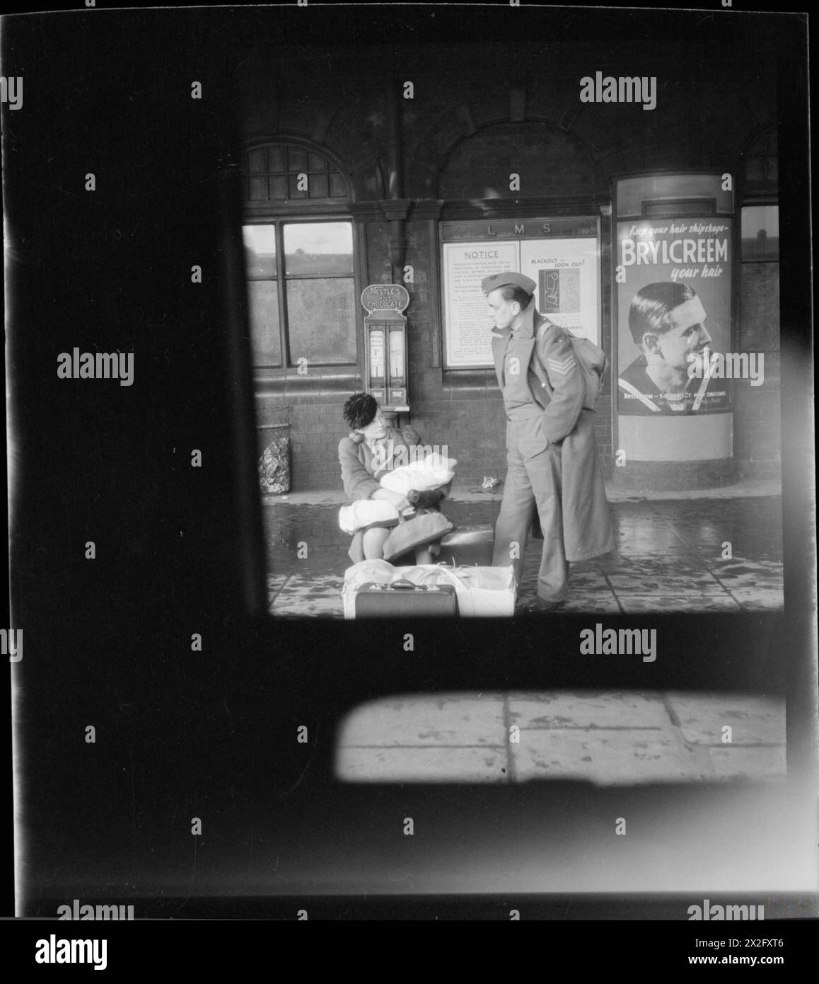 A British Army Sergeant stands with a mother and baby on a station ...