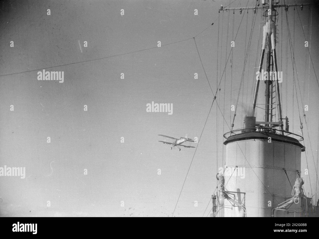 A Fairey Swordfish aircraft flies over the British destroyer HMS Kelvin ...