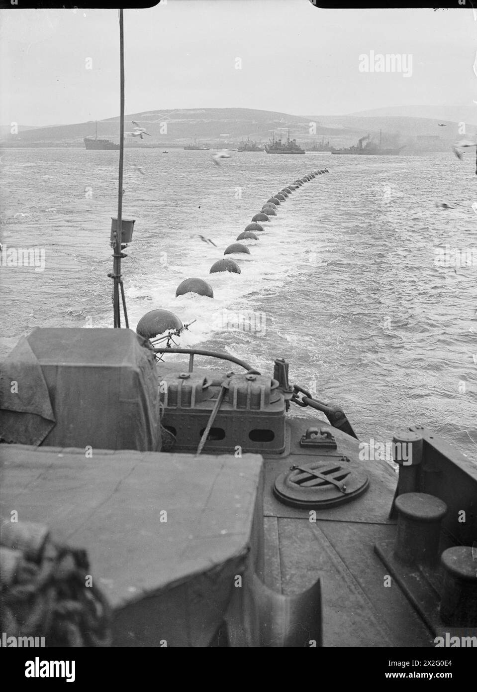 Two Royal Navy boom defence vessels, manned by WWI veterans, tow the ...