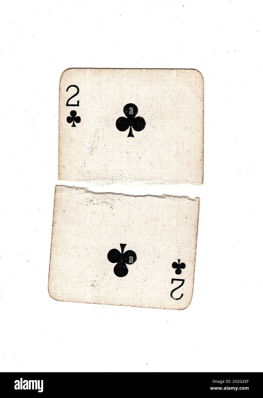 A vintage, well used two of clubs playing card torn in half on a white ...