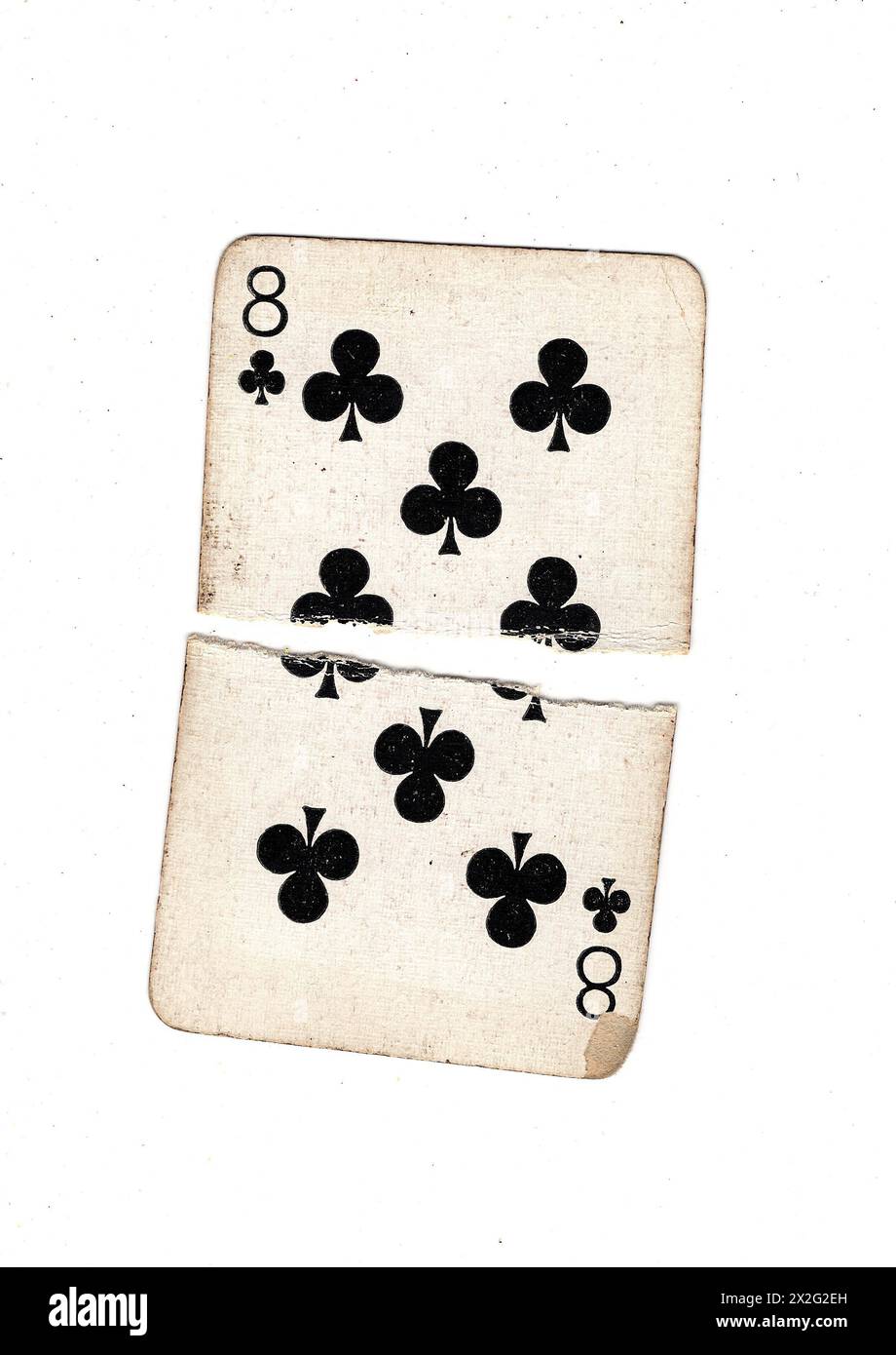 A vintage, well used eight of clubs playing card torn in half on a ...