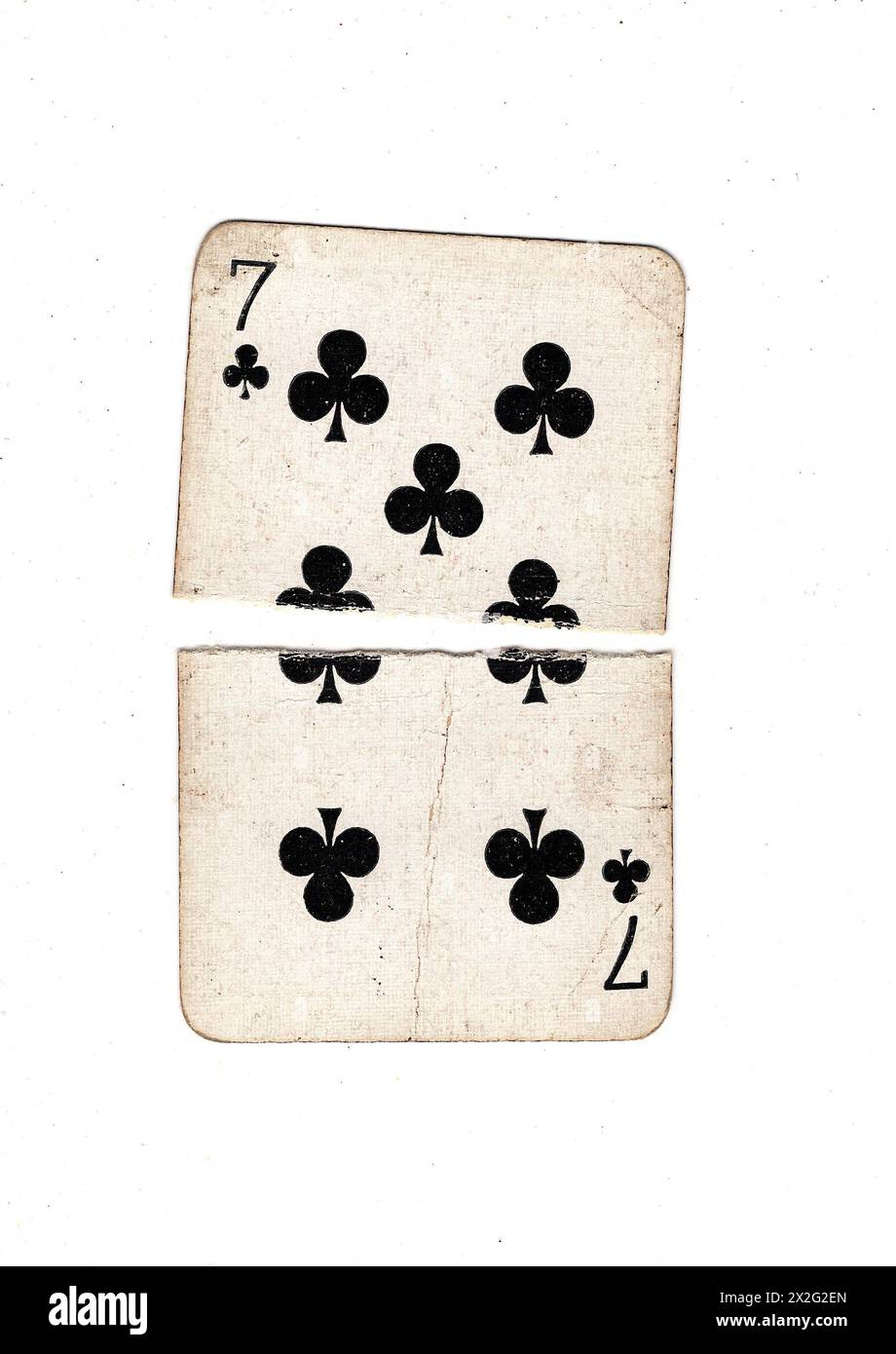A vintage, well used seven of clubs playing card torn in half on a ...