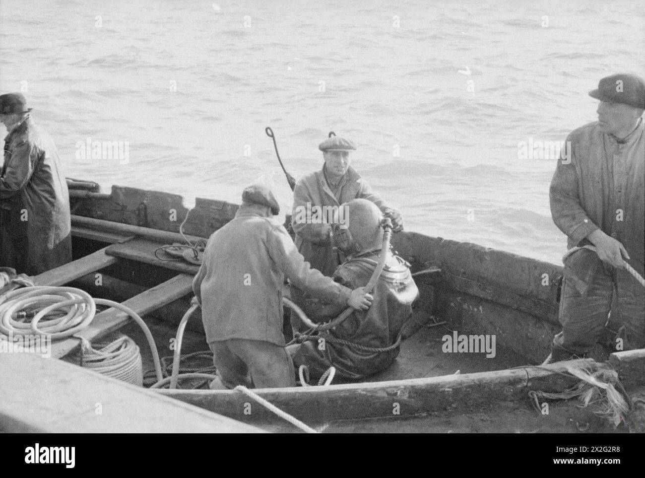 In 1940, at the Thames Estuary, Diver Gorman inspects the moorings of ...