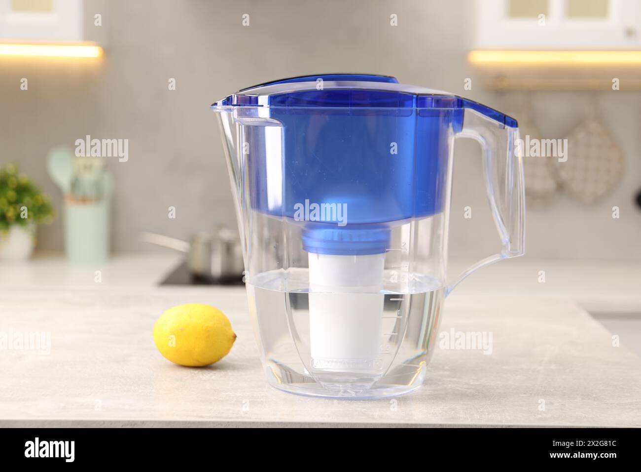 Water filter jug and lemon on light grey table in kitchen Stock Photo ...