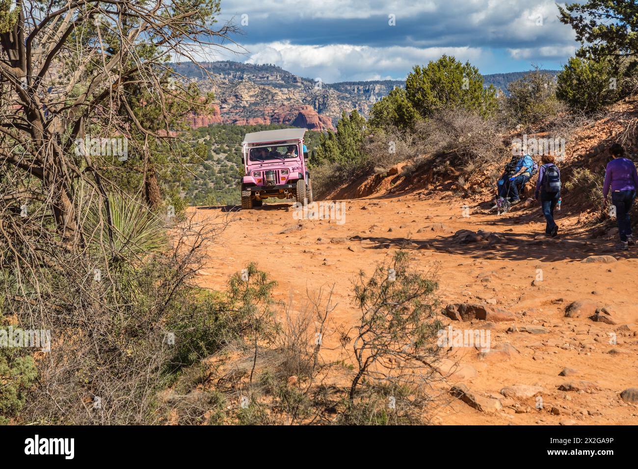 Pink jeep from Pink Jeep Tours passes hikers resting along the rough ...
