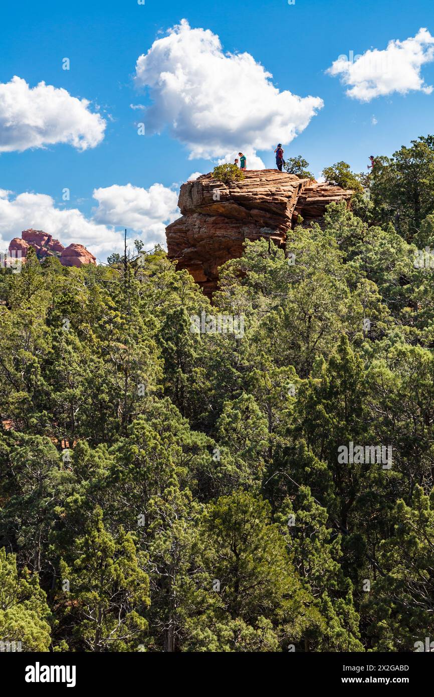 Hikers climb to the top of a red rock sandstone formation along the ...