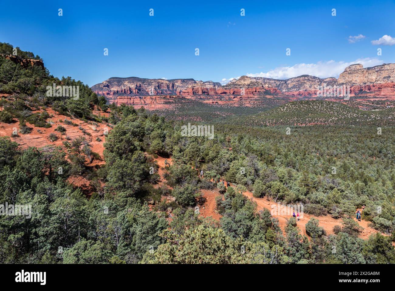 Hikers climb the slope of red rock sandstone formations along the Devil ...