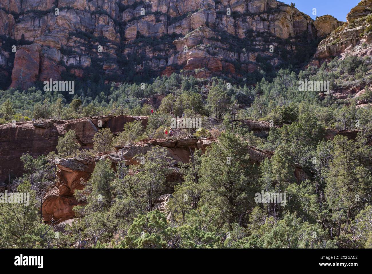 Hikers climb to multiple levels of a red rock sandstone formation along ...