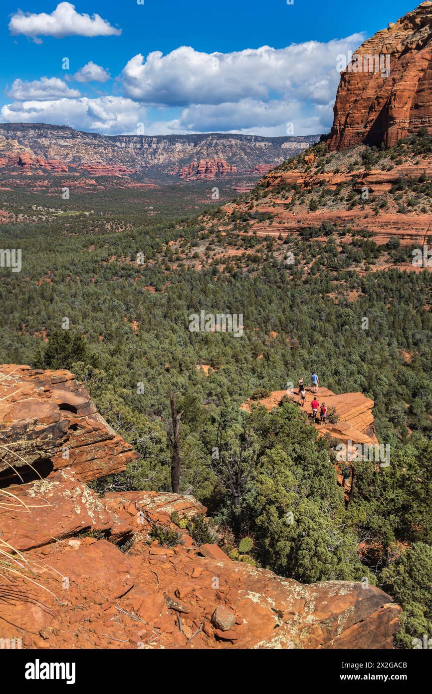 Hikers climb to the top of a red rock sandstone formation along the ...
