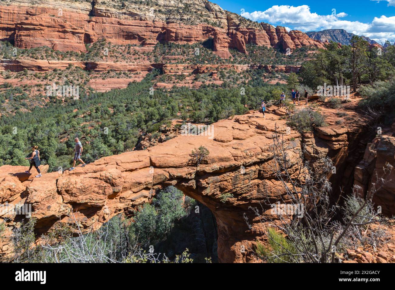 Hikers cross the Devil's Bridge natural arch along the Devil's Bridge Trail in Sedona, Arizona ...