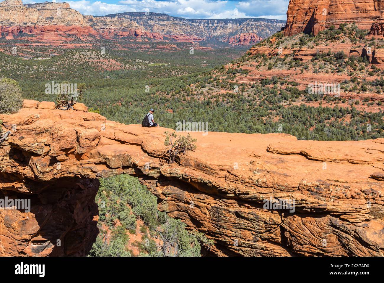 Hiker sits on the edge of the Devil's Bridge natural arch along the ...