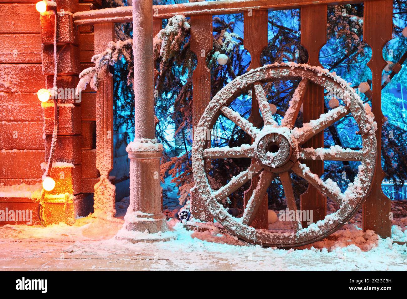 Wooden wheel in snow stand near beautiful railing; Spruce in snow ...