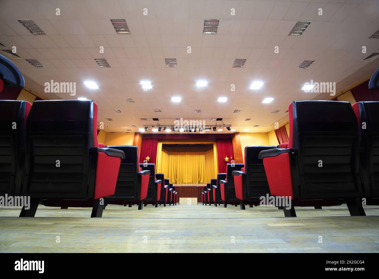 Concert hall and empty stage, many rows of red seats and stage with ...