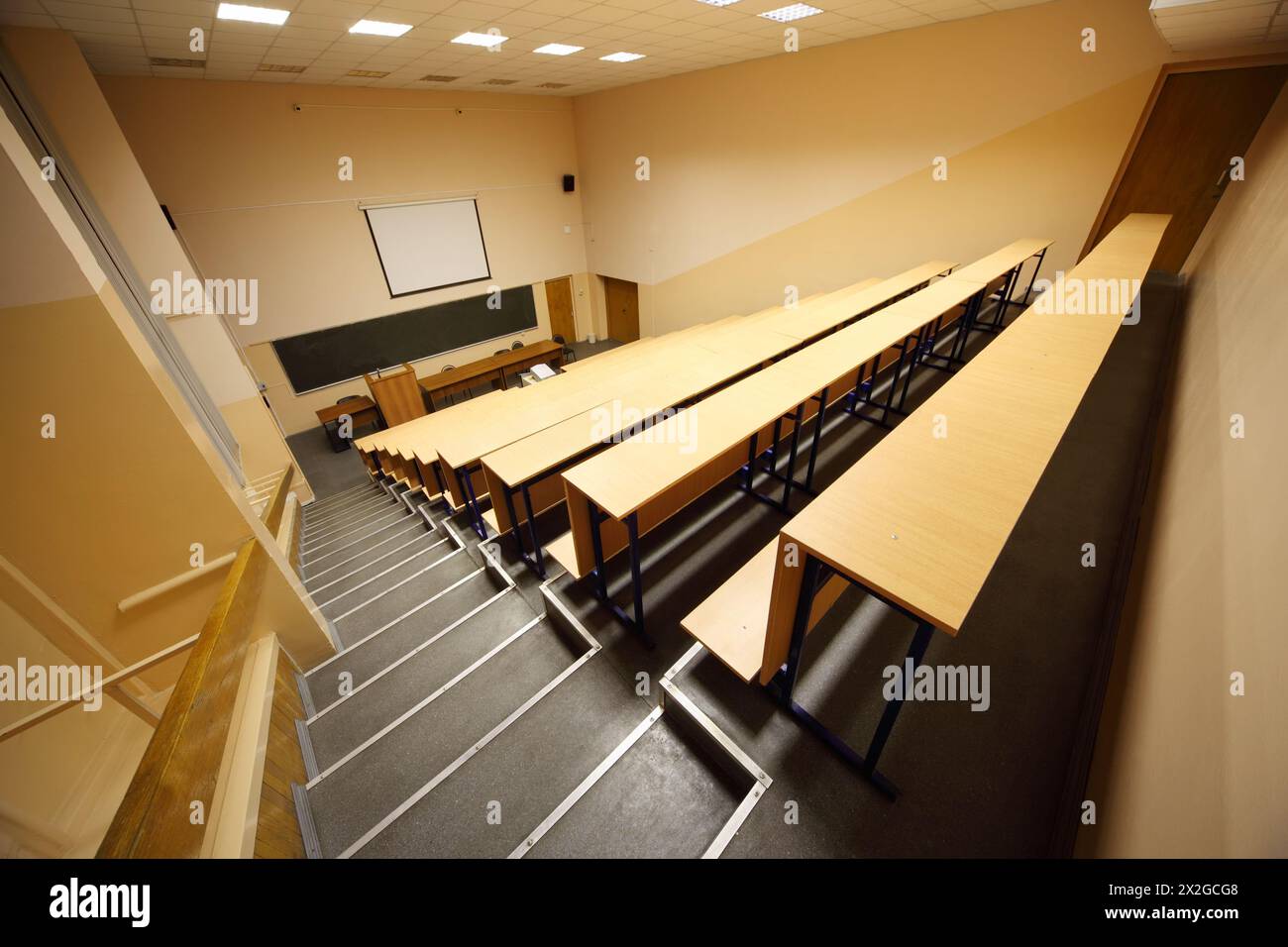 Inside university lecture hall; big blackboard, wooden desks and ...
