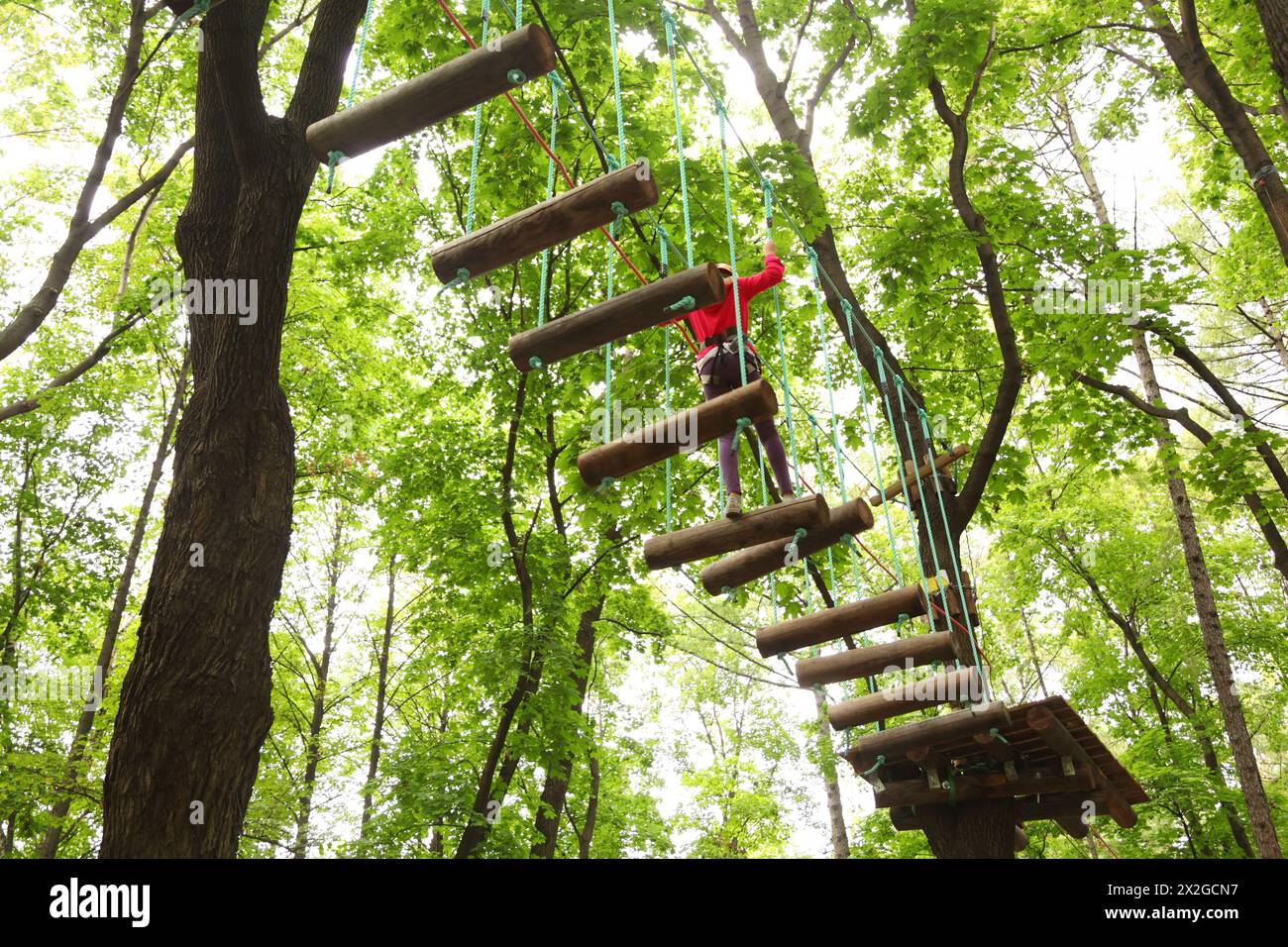 Girl wearing red shirt and helmet on course with safety equipment in ...