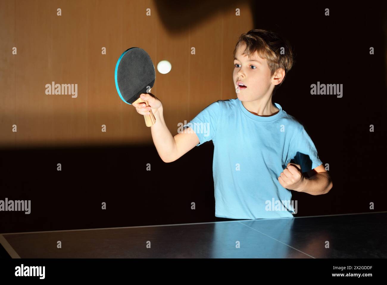 little boy wearing blue shirt playing ping pong; concentrated face Stock Photo - Alamy