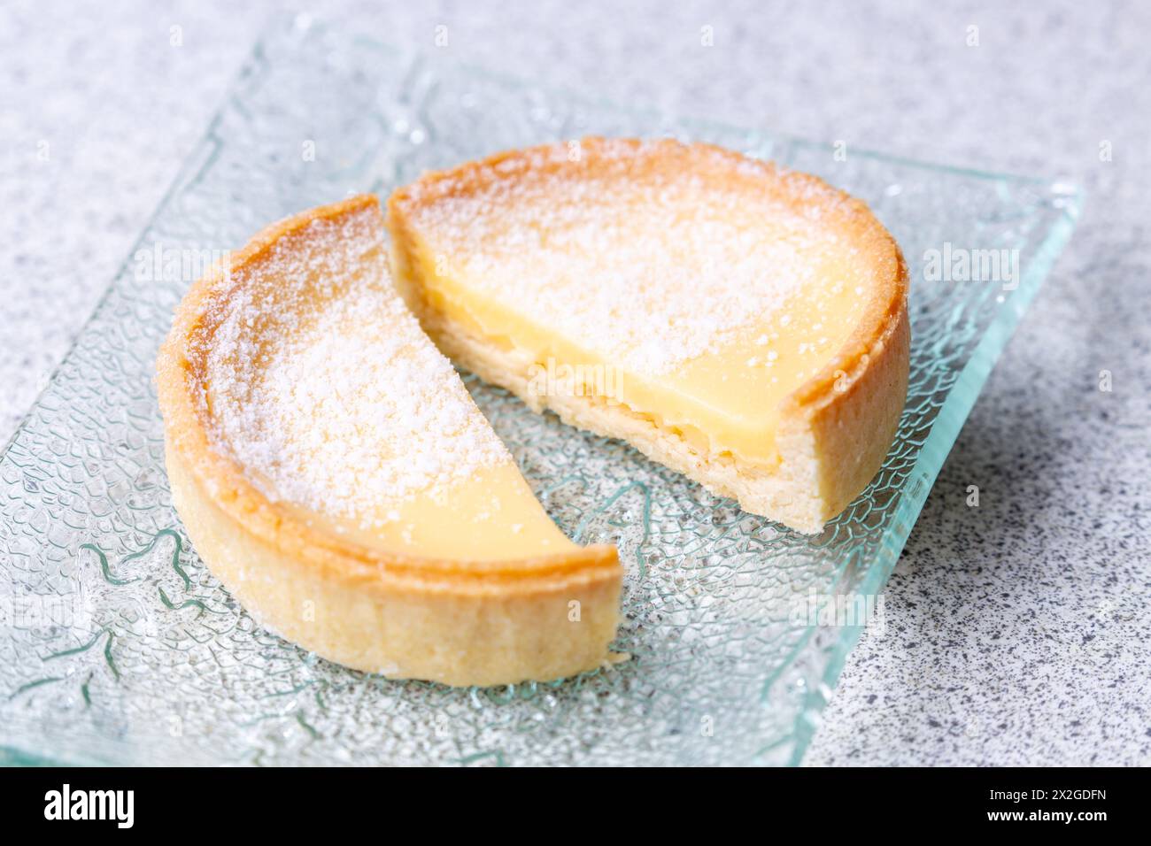 A lemon tart ( tarte au citron) cut in two and dusted with icing sugar ...
