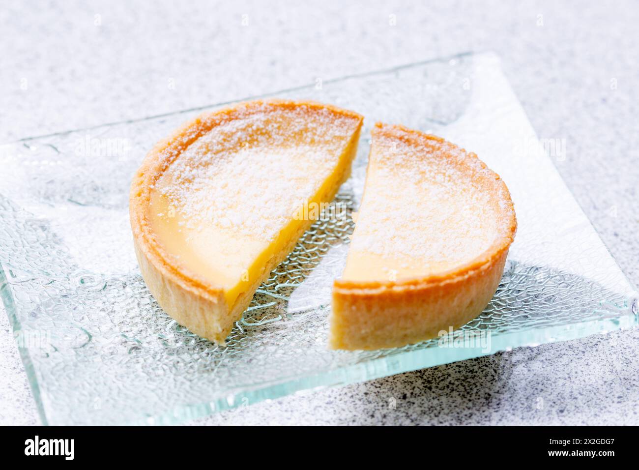A lemon tart ( tarte au citron) cut in two and dusted with icing sugar ...