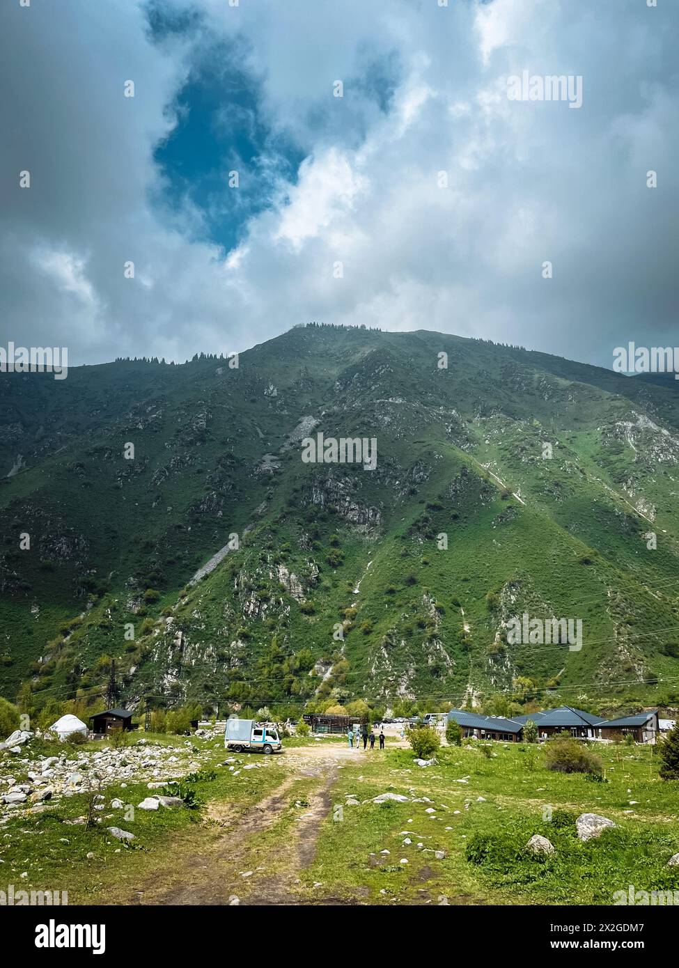 Scenic mountain valley landscape with distant village, blue sky, clouds ...
