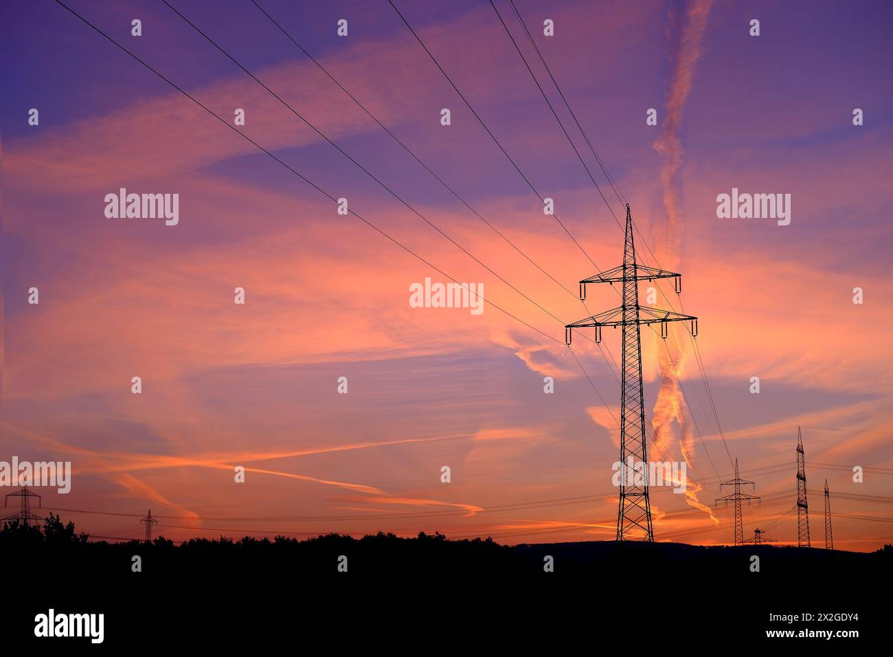 beautiful sunset landscape, sky with airplane trail lines, power towers ...