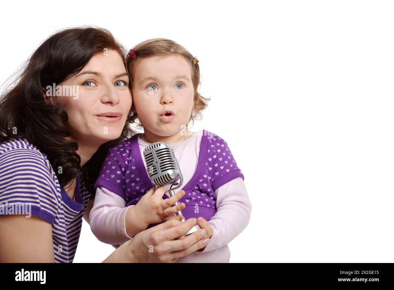 Mother with little daughter cheek to cheek sing into microphone Stock ...