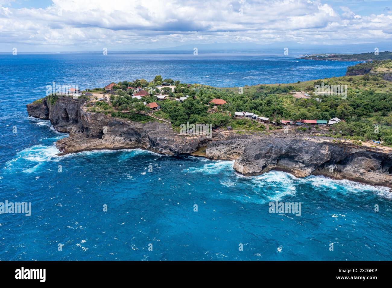 An aerial shot shows a cliff by the azure ocean, blending with the sky ...