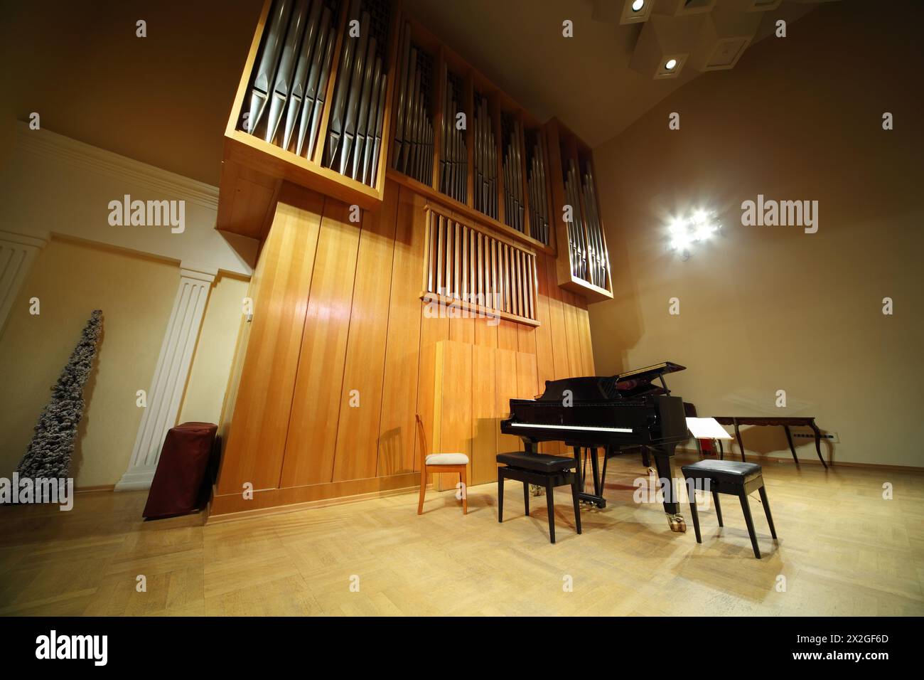 Massive wooden high pipe organ and black concert grand piano in light ...