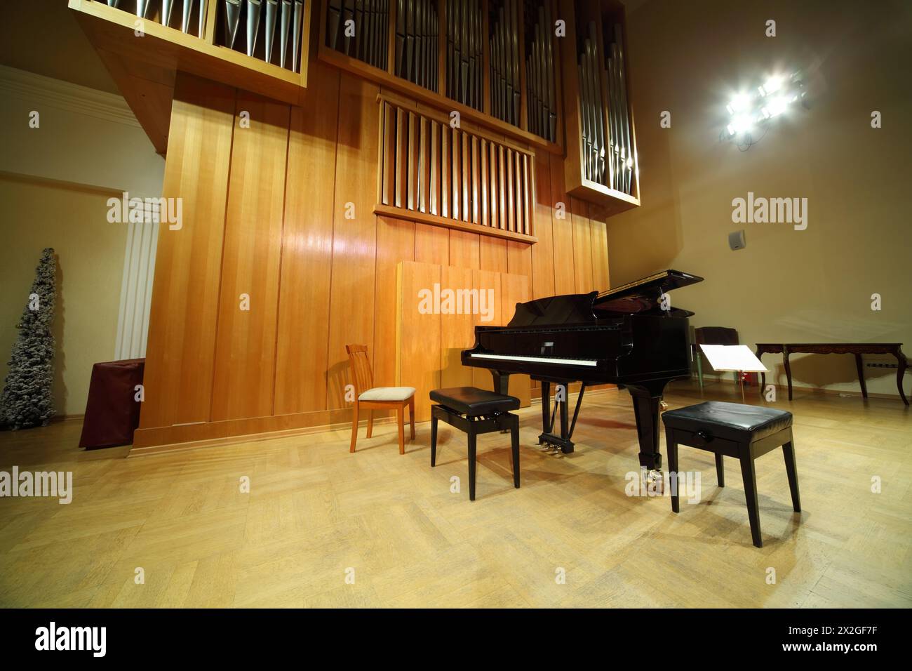 Massive wooden pipe organ and black concert grand piano in light hall ...