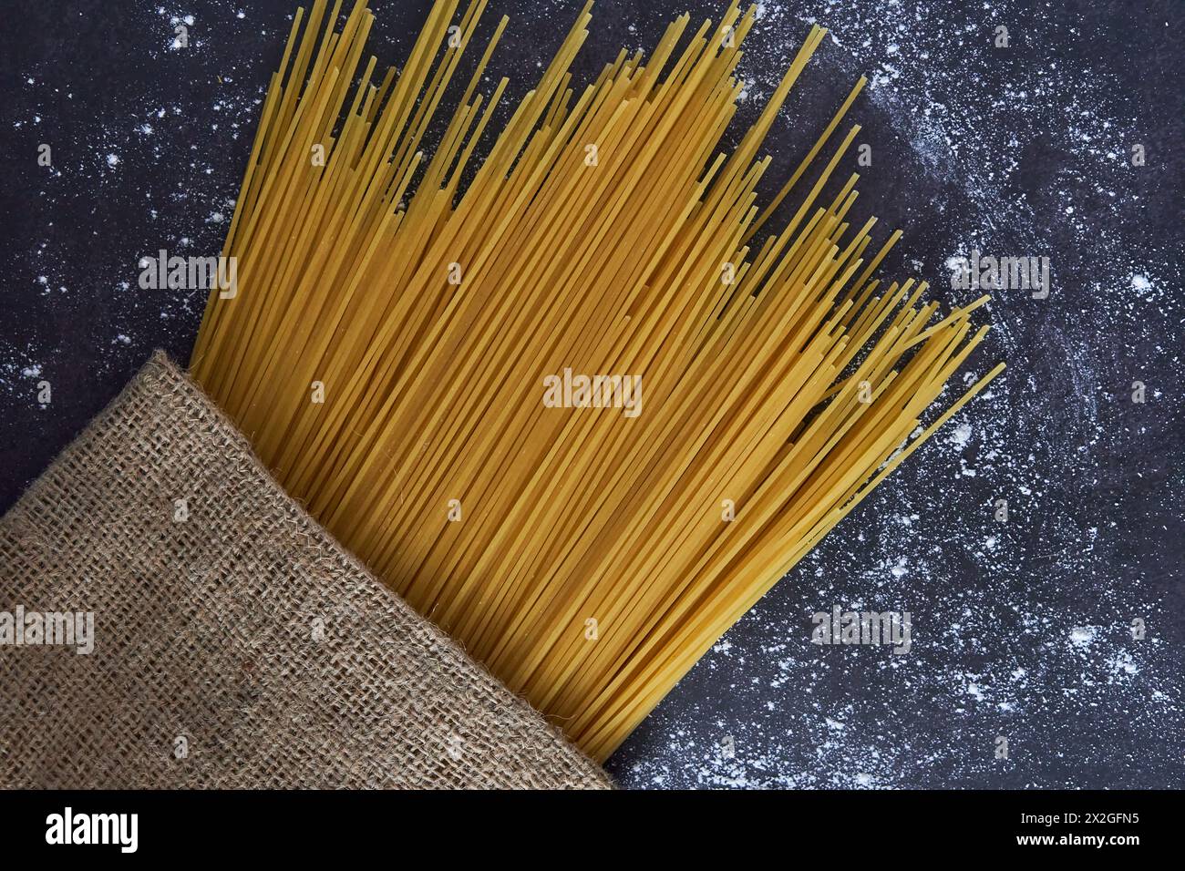 bunch of dried spaghetti in a rustic bag, zenithal shot on black ...