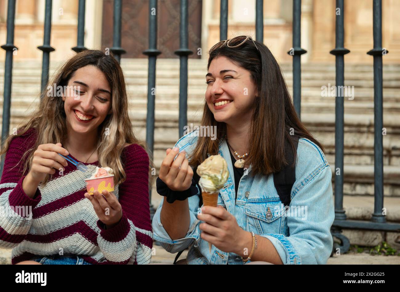 Two Caucasian girls sitting on a staircase eating ice cream and ...