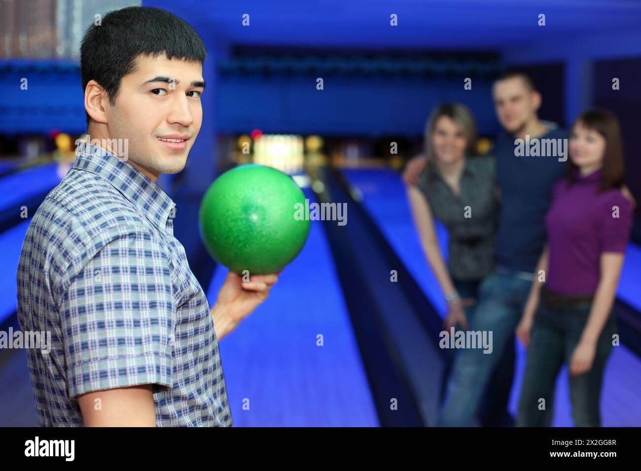One fellow stands sideways and holds ball for playing in bowling and ...