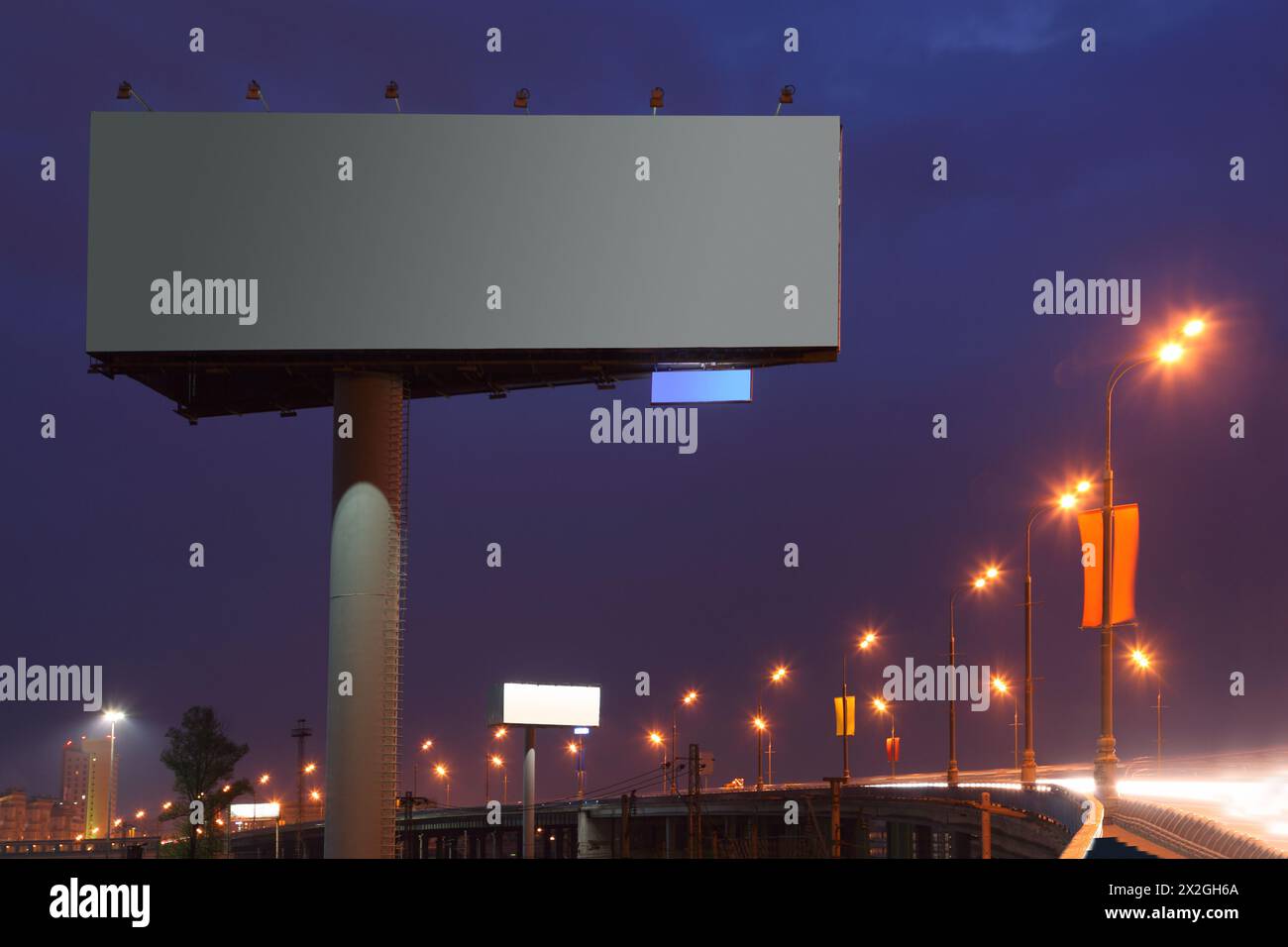 Big gray billboard with illumination at night, road, bridge and row of ...