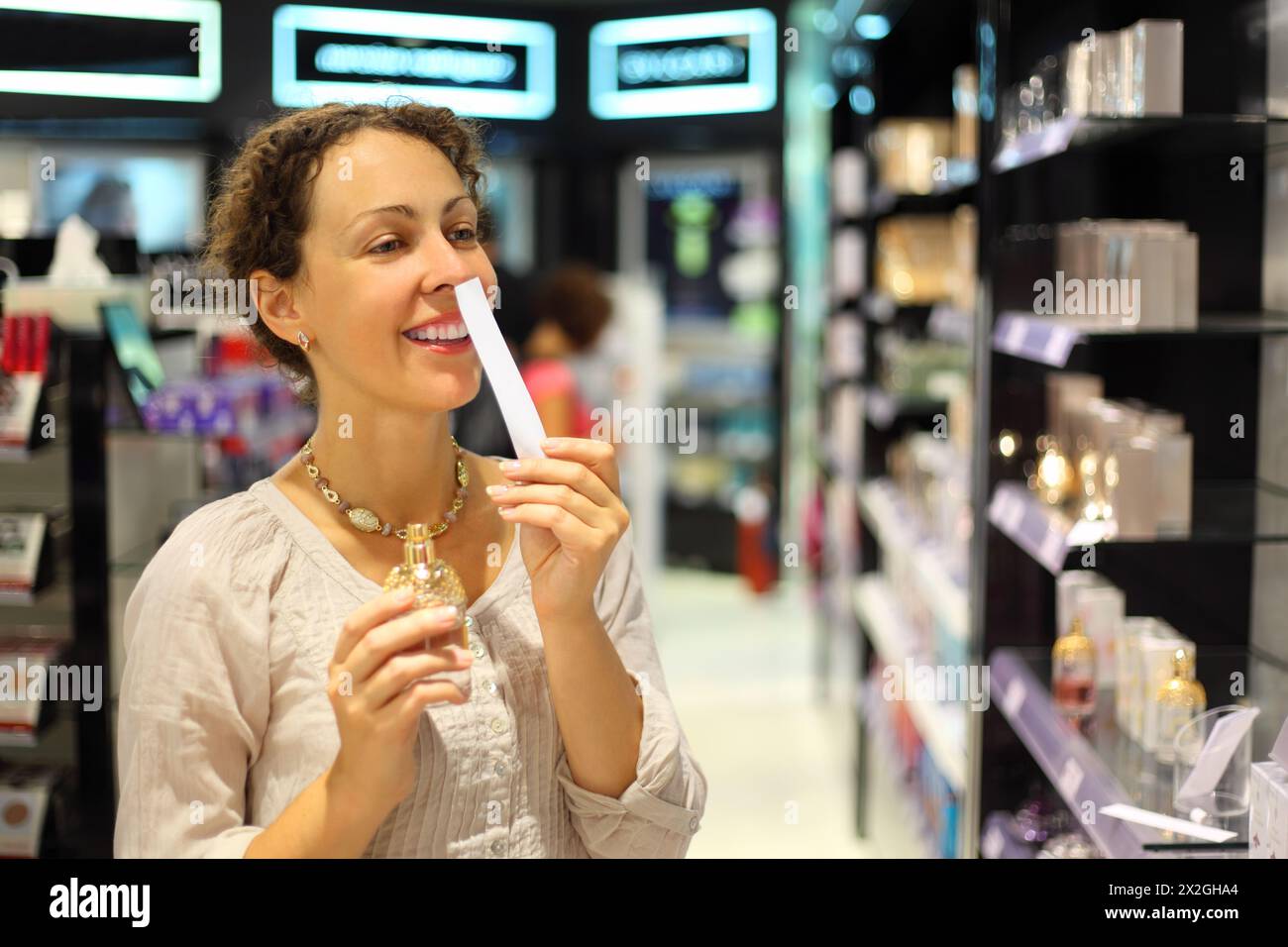 beautiful young woman choose perfume in perfume shop, big assortment ...