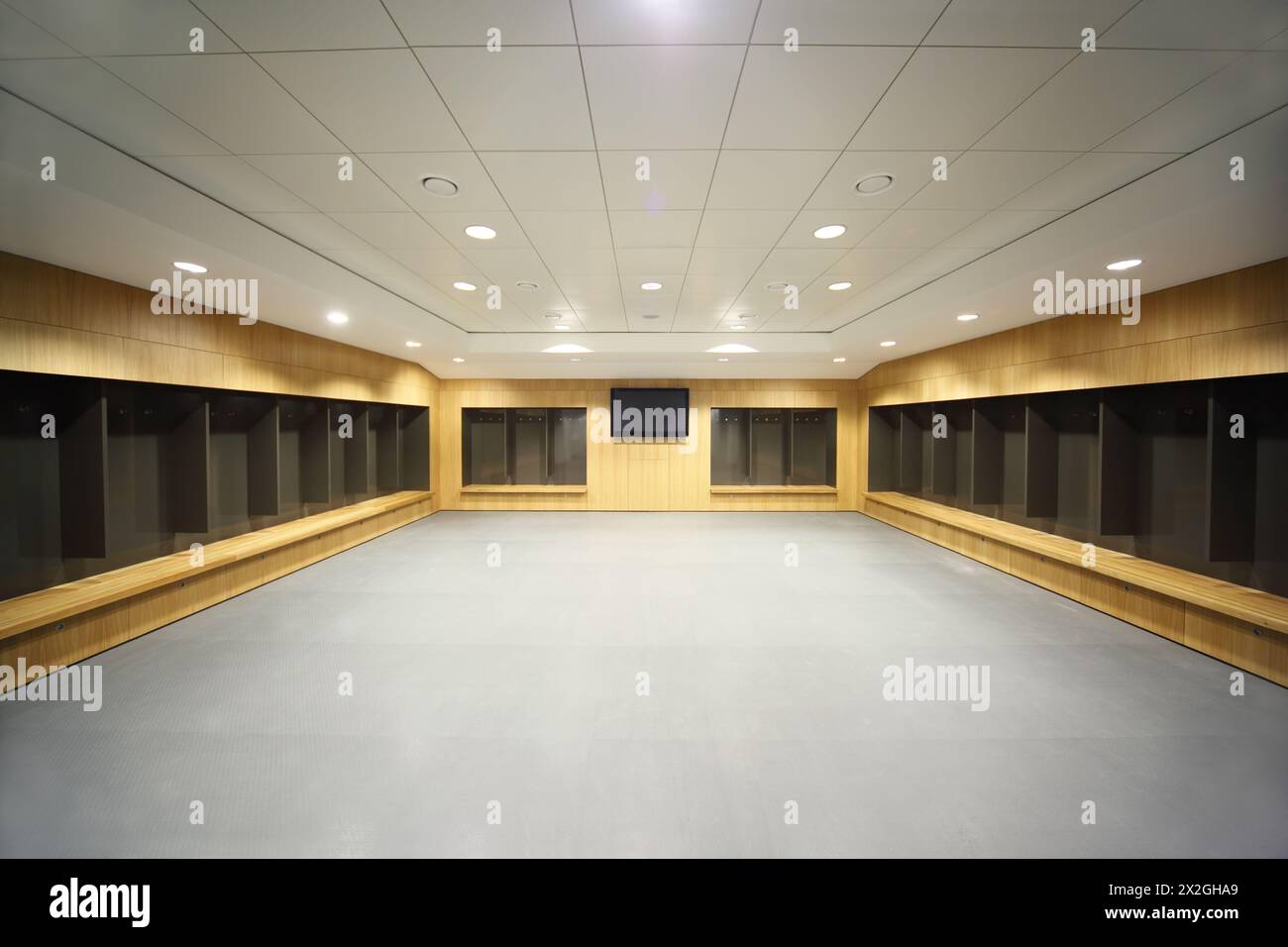 large clean locker room. gray floor and ceiling, big televisor on wall ...
