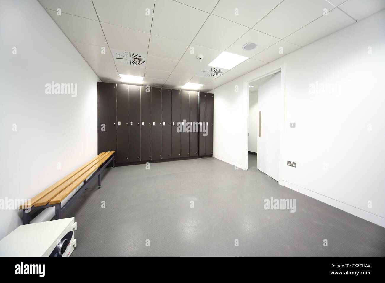 large clean locker room, gray floor and ceiling, black closet, bench ...