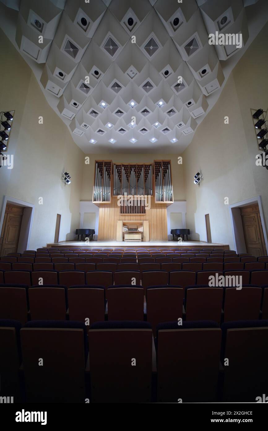 Massive wooden pipe organ in empty concert hall; brightly lit stage ...